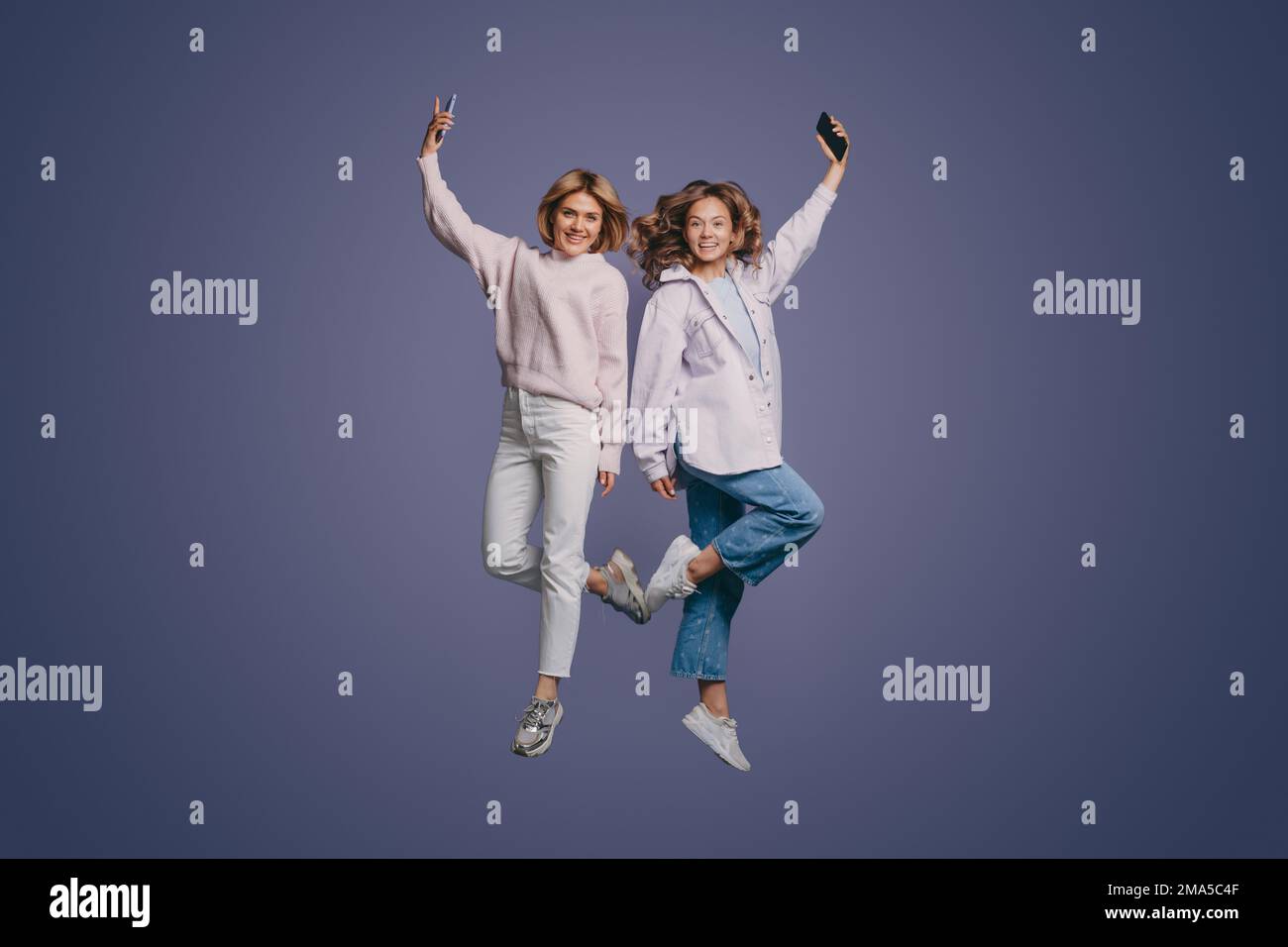 Two girls posing giving high fives with their legs, holding their hands ...