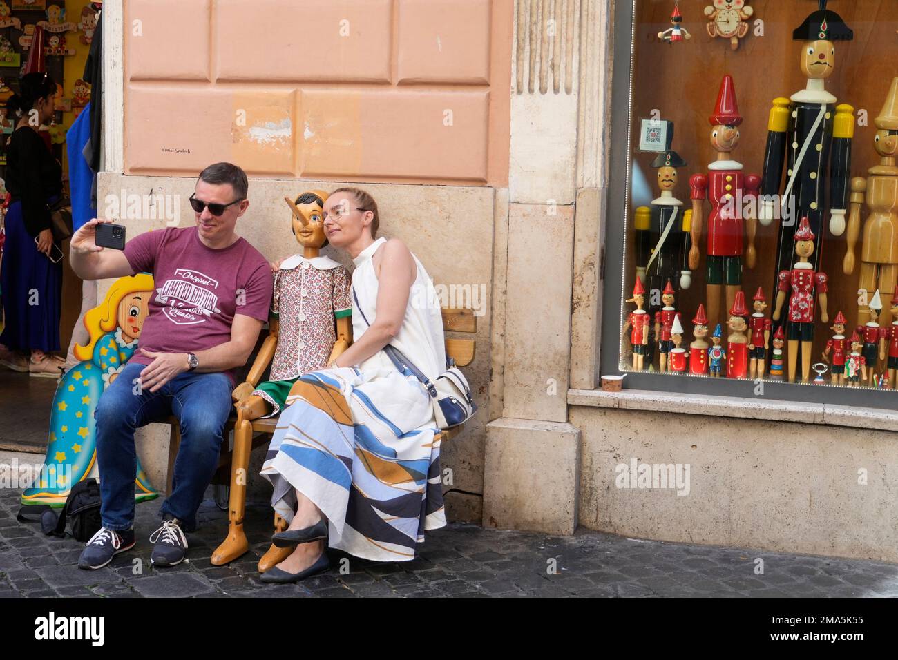 Tourists pose for a souvenir picture near a wooden puppet of Pinocchio ...