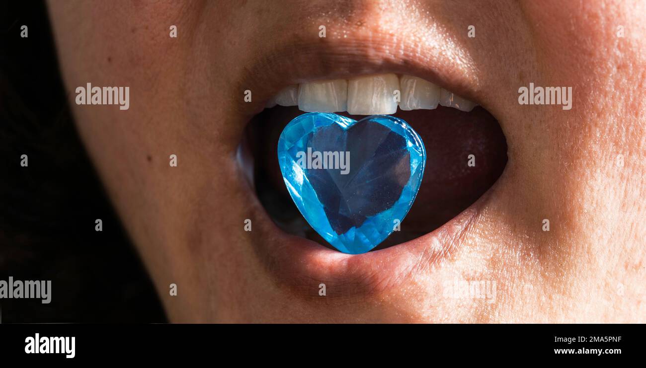 Woman bites off blue lollipop in the shape of heart Stock Photo - Alamy