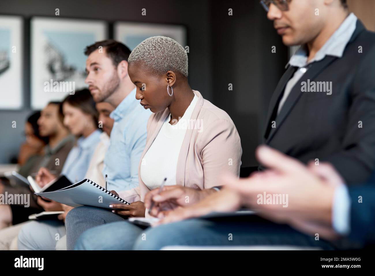 Sit down and listen. a group of businesspeople making notes during a ...