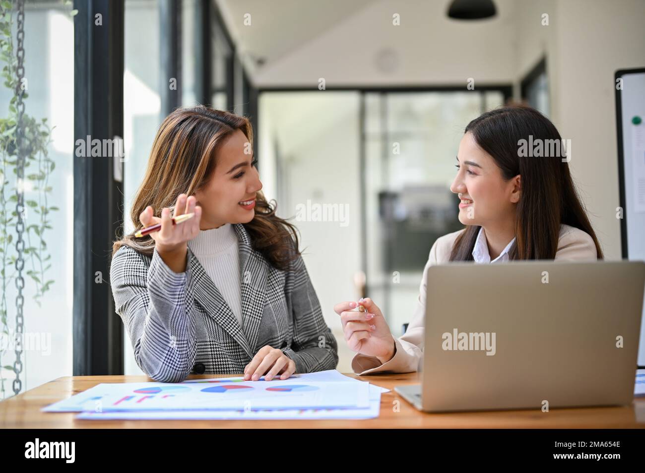 Two cheerful and beautiful millennial Asian businesswomen or office ...