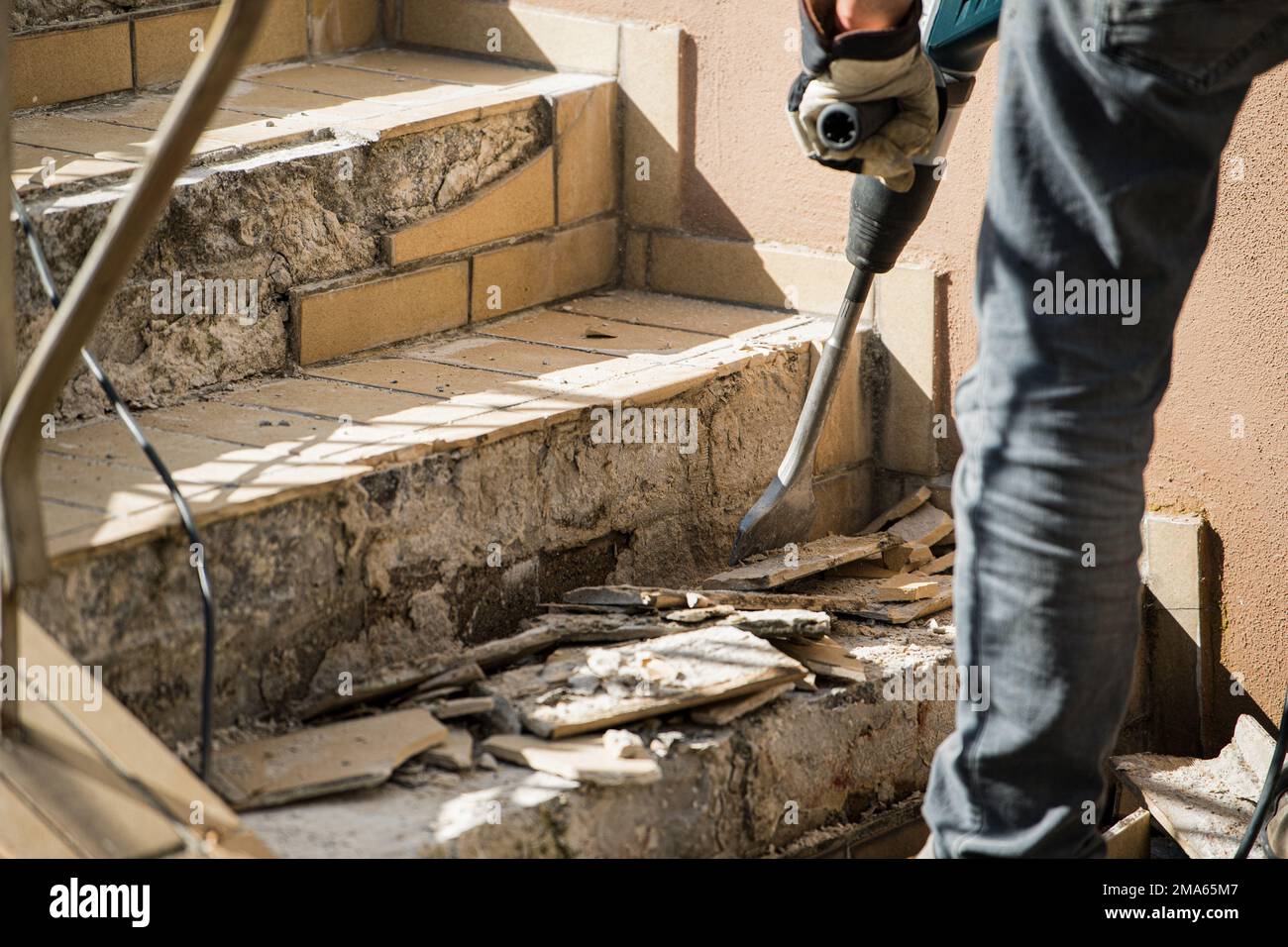 Man removes tiles from a stair using a hammer drill Stock Photo - Alamy