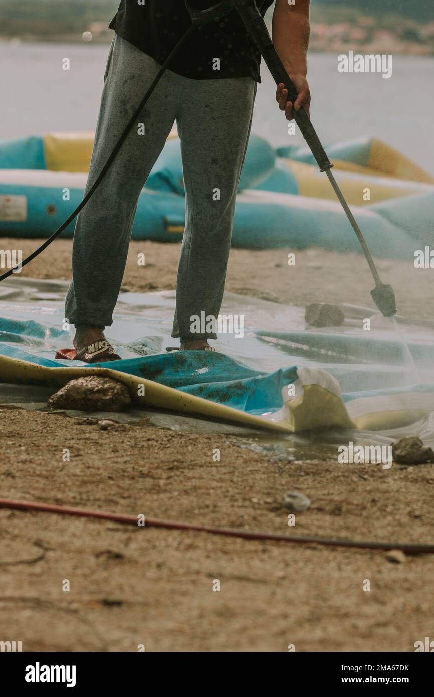 Man washing a lifeline on the beach with a washer Stock Photo - Alamy