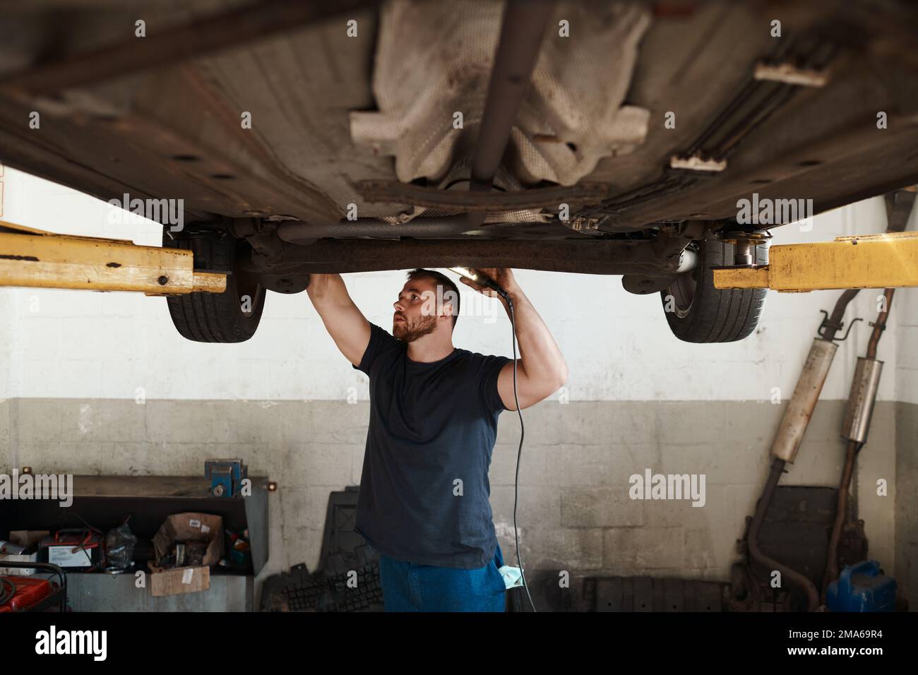 Mechanic standing fixing under lifted hi-res stock photography and ...