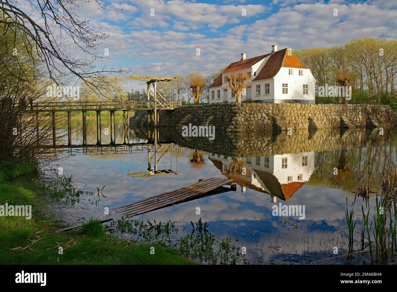 Manor house reflected in the water of a lake, small island, old wooden ...