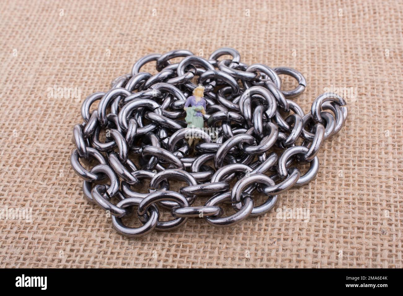 Woman figurine on steel chains on a textured surface on display Stock ...