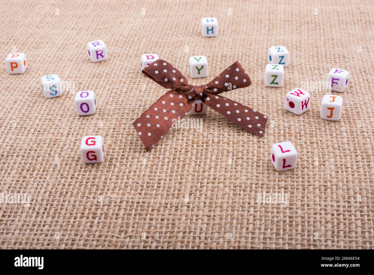 A ribbon and scattered dice-sized alphabet cubes on a textured surface ...