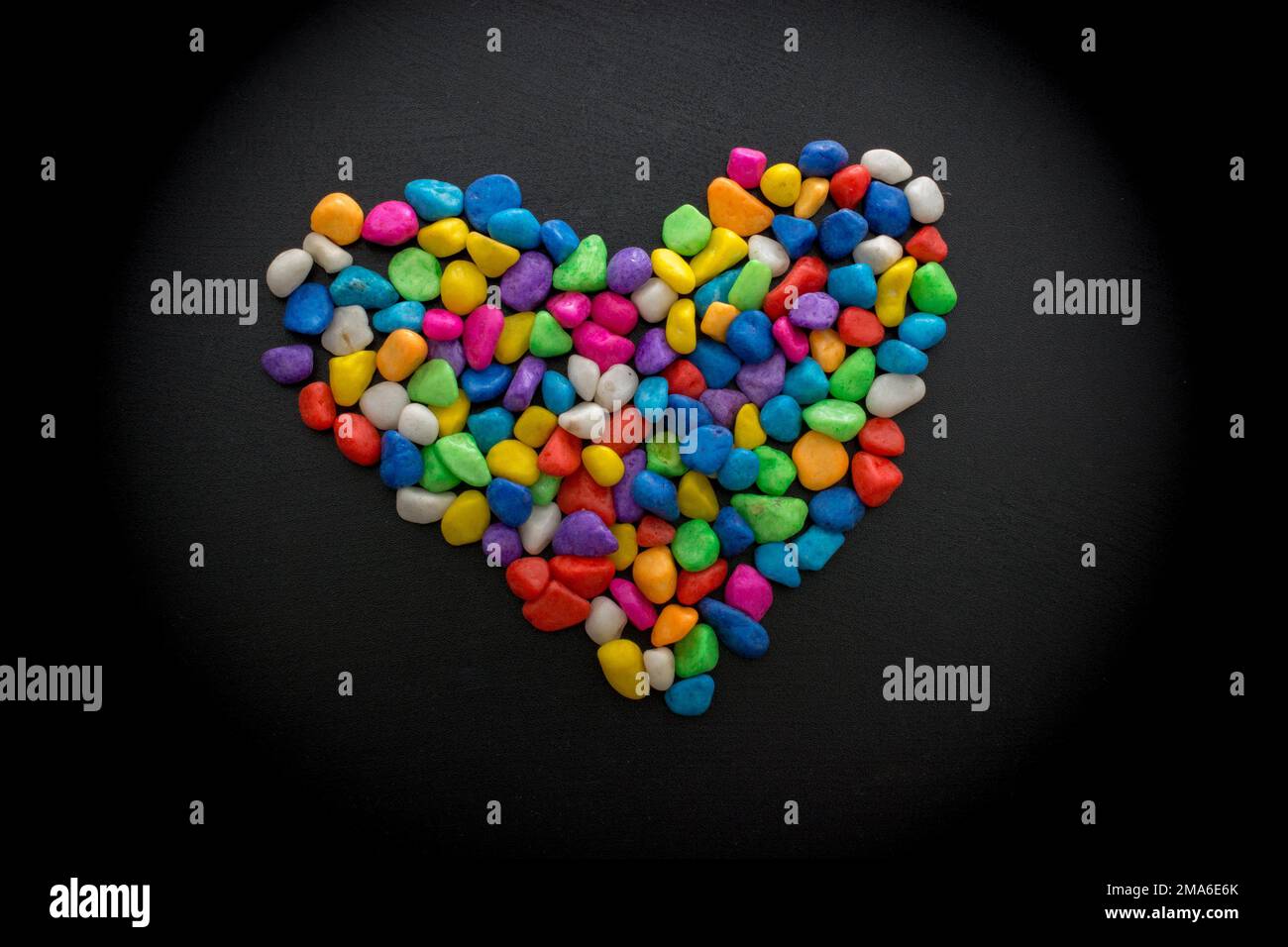 Colorful little pebbles form heart shape on black Stock Photo - Alamy