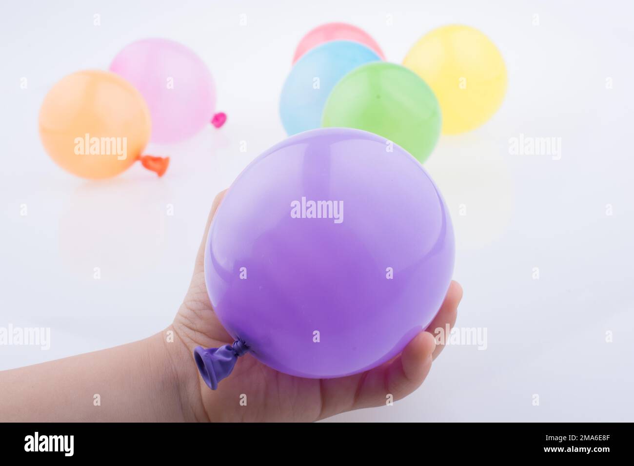 Hand holding a Colorful small balloon with colorful baloons on the ...