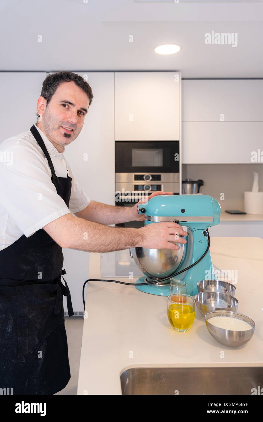 A man baker bakes a red velvet cake at home, preparing the cake in the ...