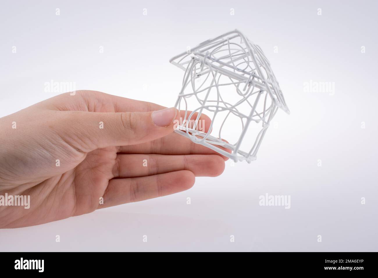 Little model house made of white metal wire in hand Stock Photo - Alamy