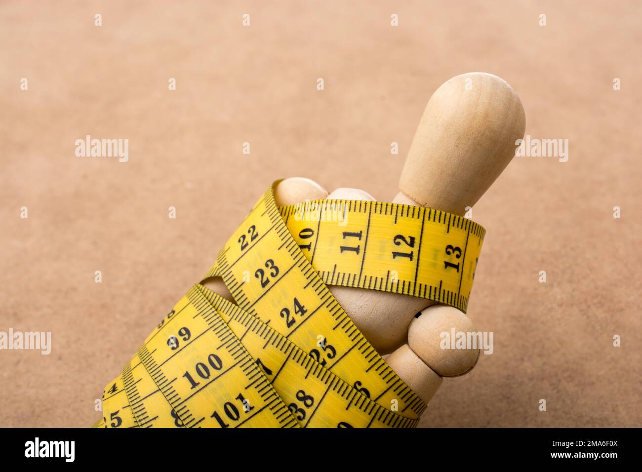 Yellow color measuring tape wrapped on wooden man Stock Photo - Alamy