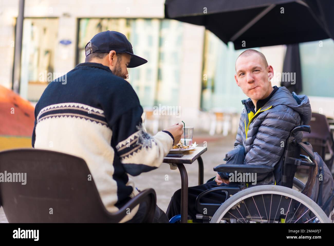 Friends eating in a restaurant terrace, disabled person, wheelchair ...