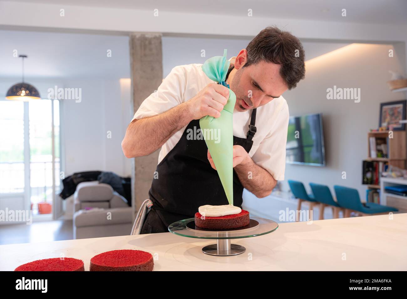 A challenger man bakes a red velvet cake at home, assembling the triple ...