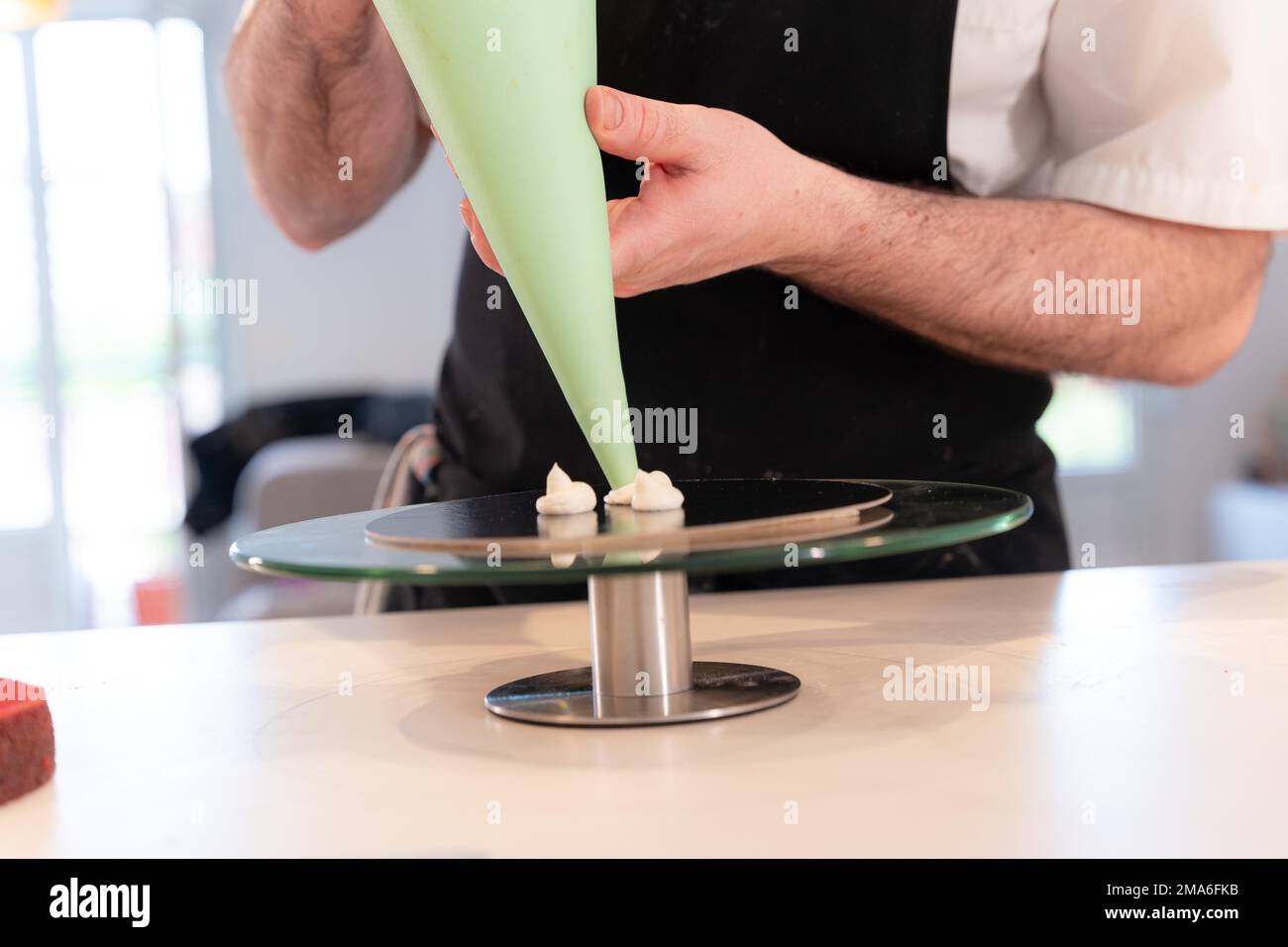 Hands of a man bakes a red velvet cake at home, assembling the triple ...