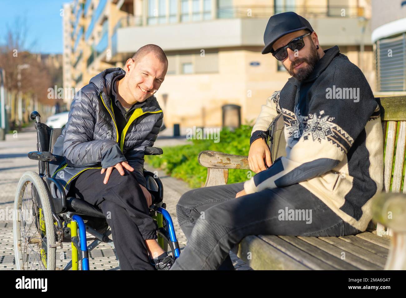 Portrait of disabled person in wheelchair with friend sitting having ...