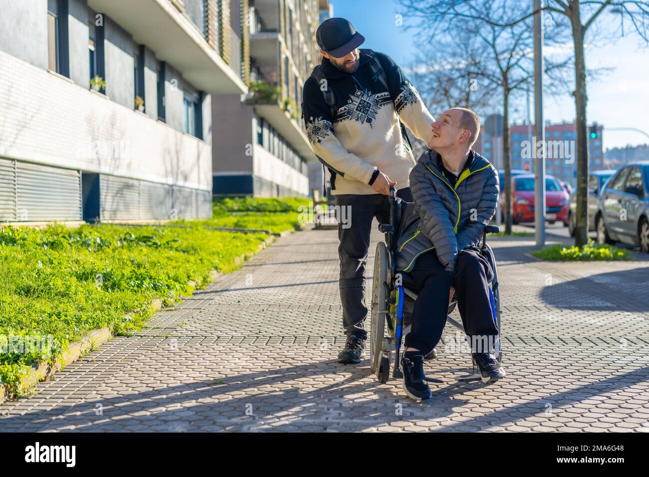 Disabled person walking having fun with friend in wheelchair on the ...