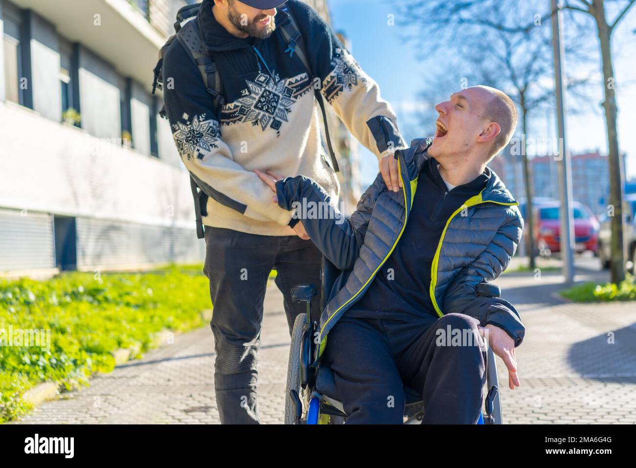 Disabled person in a wheelchair laughing with a friend in a chair on ...