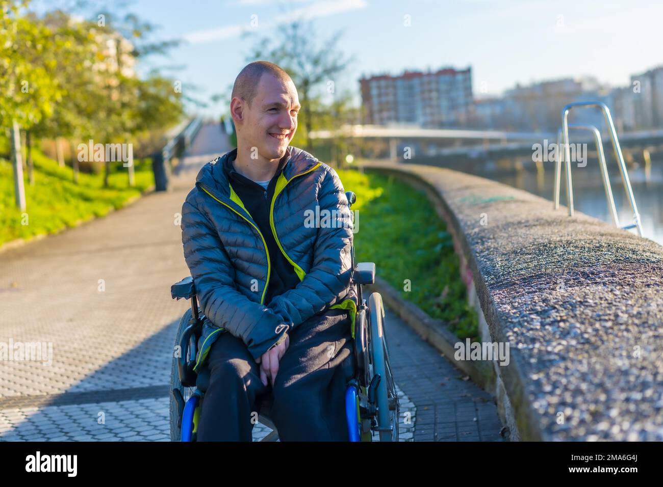 Portrait of a disabled person in a wheelchair having fun in a city park ...