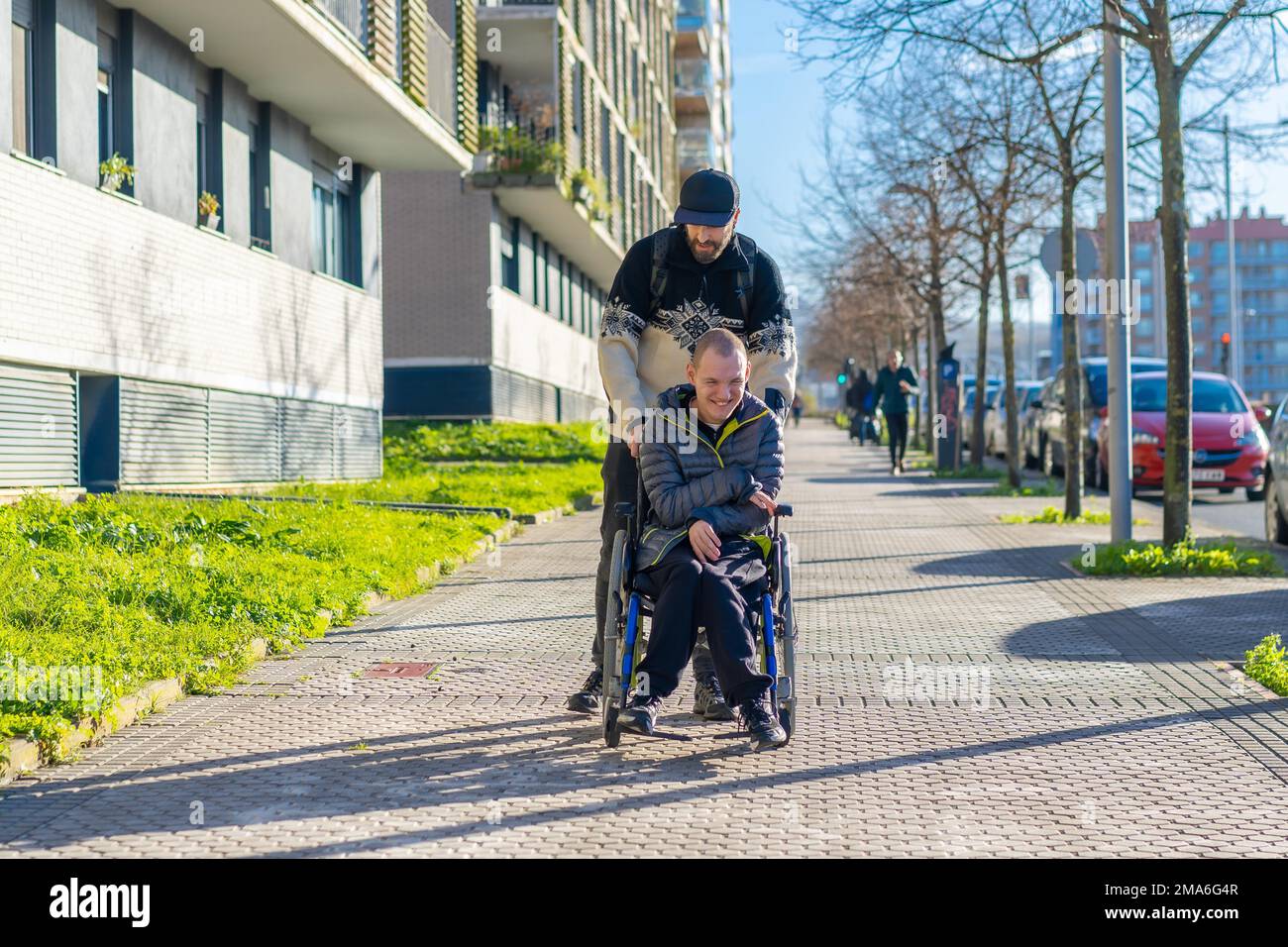 Disabled person walking having fun with friend in wheelchair on the ...