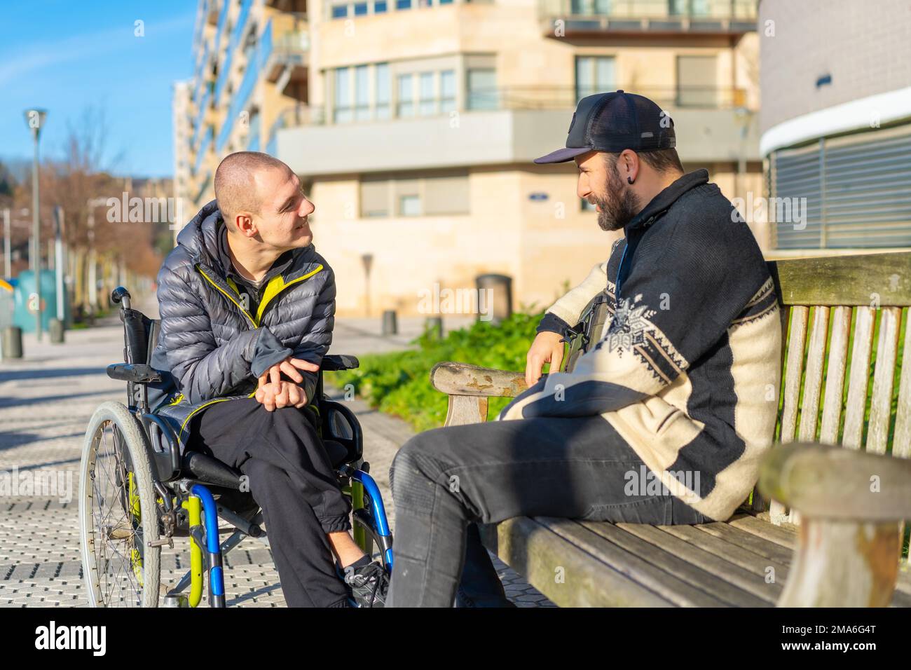 Disabled person in a wheelchair with a friend sitting having fun and ...