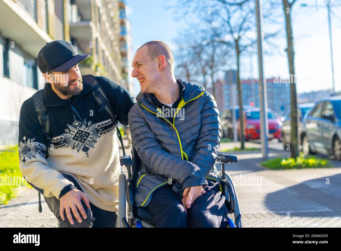 A disabled person in a wheelchair with a friend smiling, handicapped ...