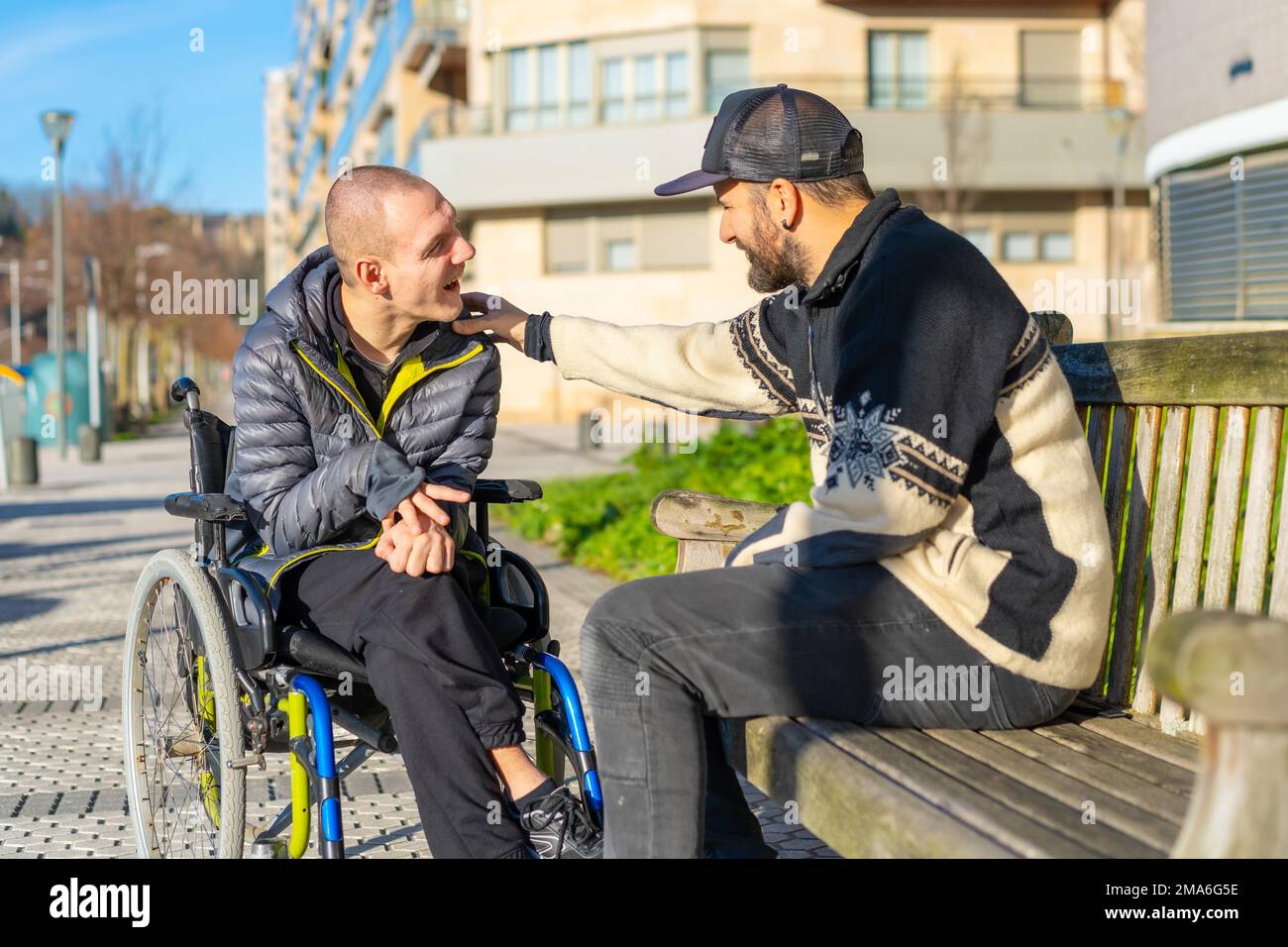 Disabled person in a wheelchair with a friend sitting having fun and ...
