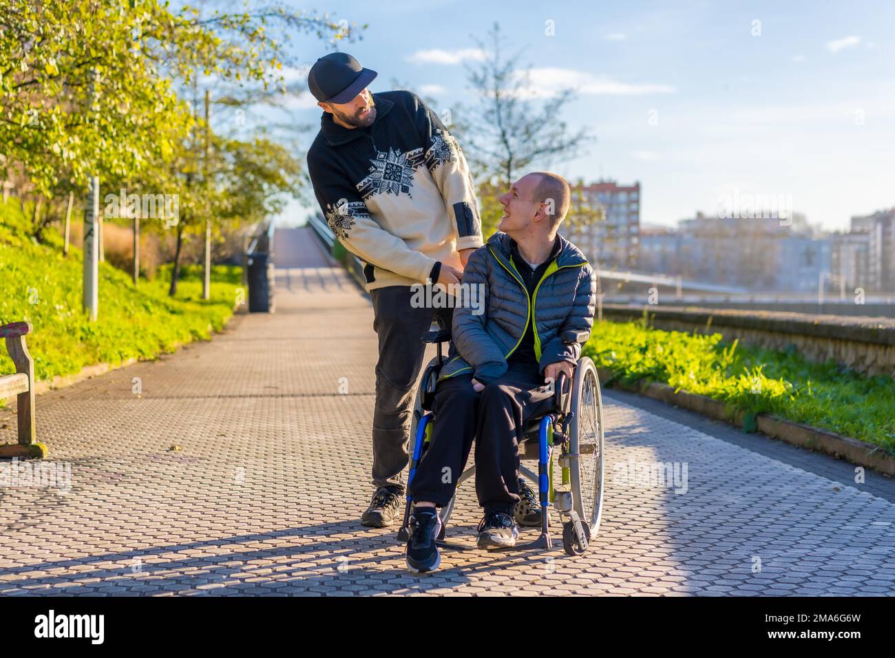 A disabled person in a wheelchair with an assistant enjoying a walk in ...