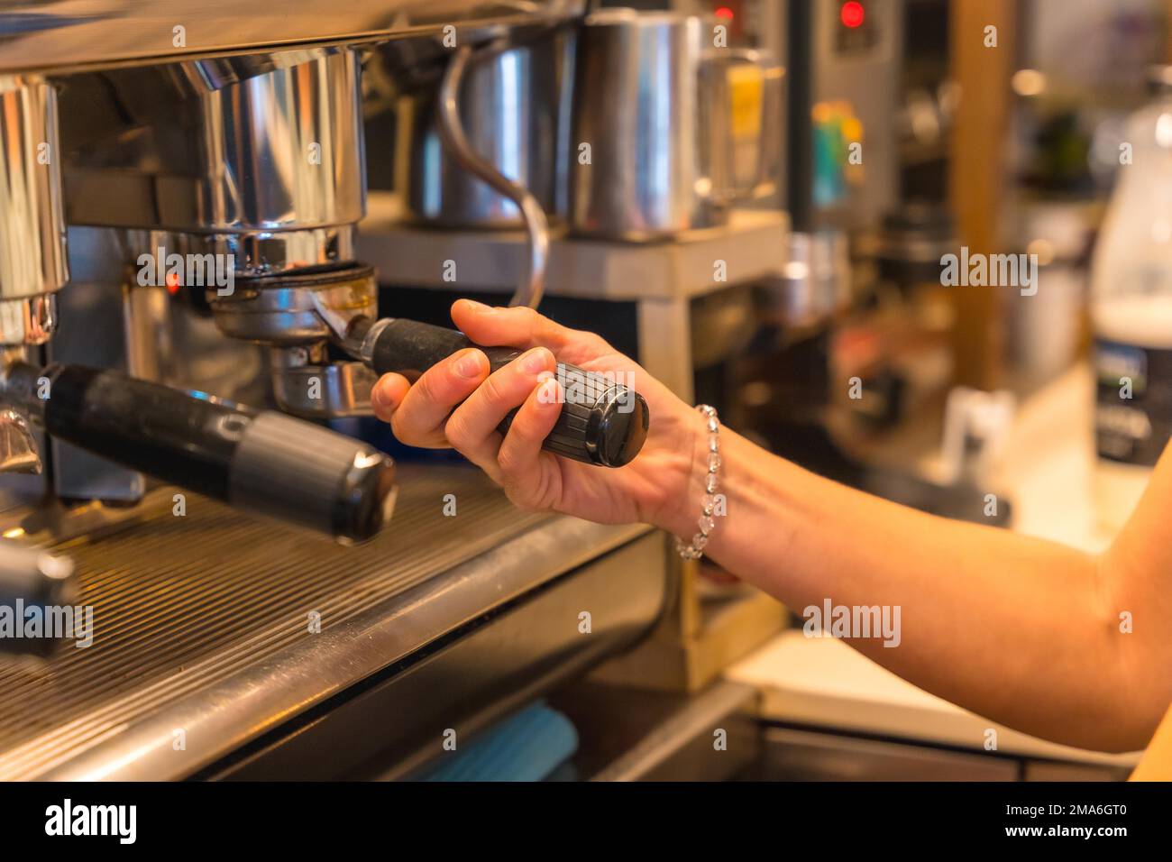 Hands of female coffee shop owner preparing coffee in a coffee machine ...