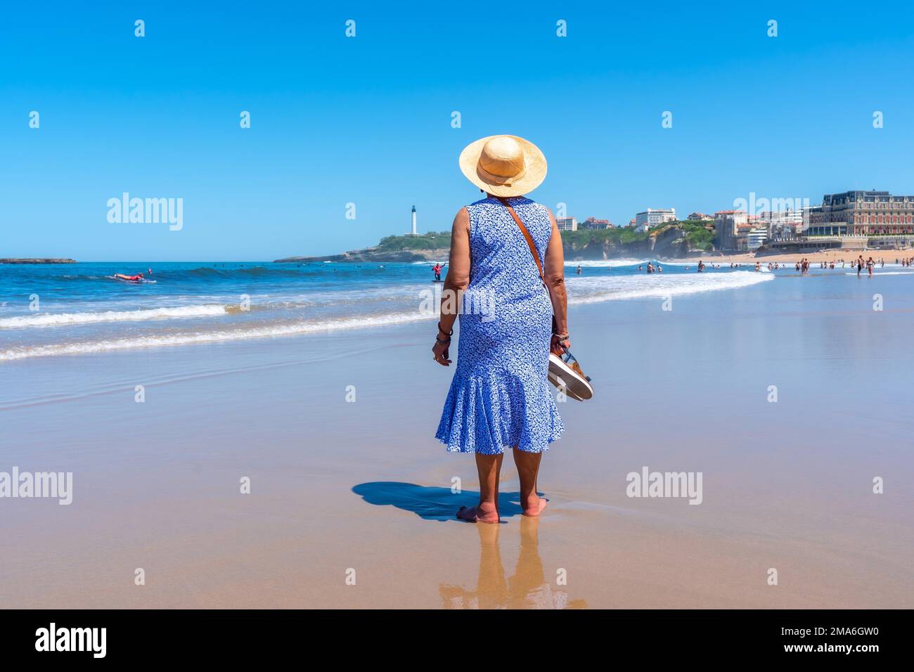 An elderly woman walking on the beach, South West resort town, Biarritz ...