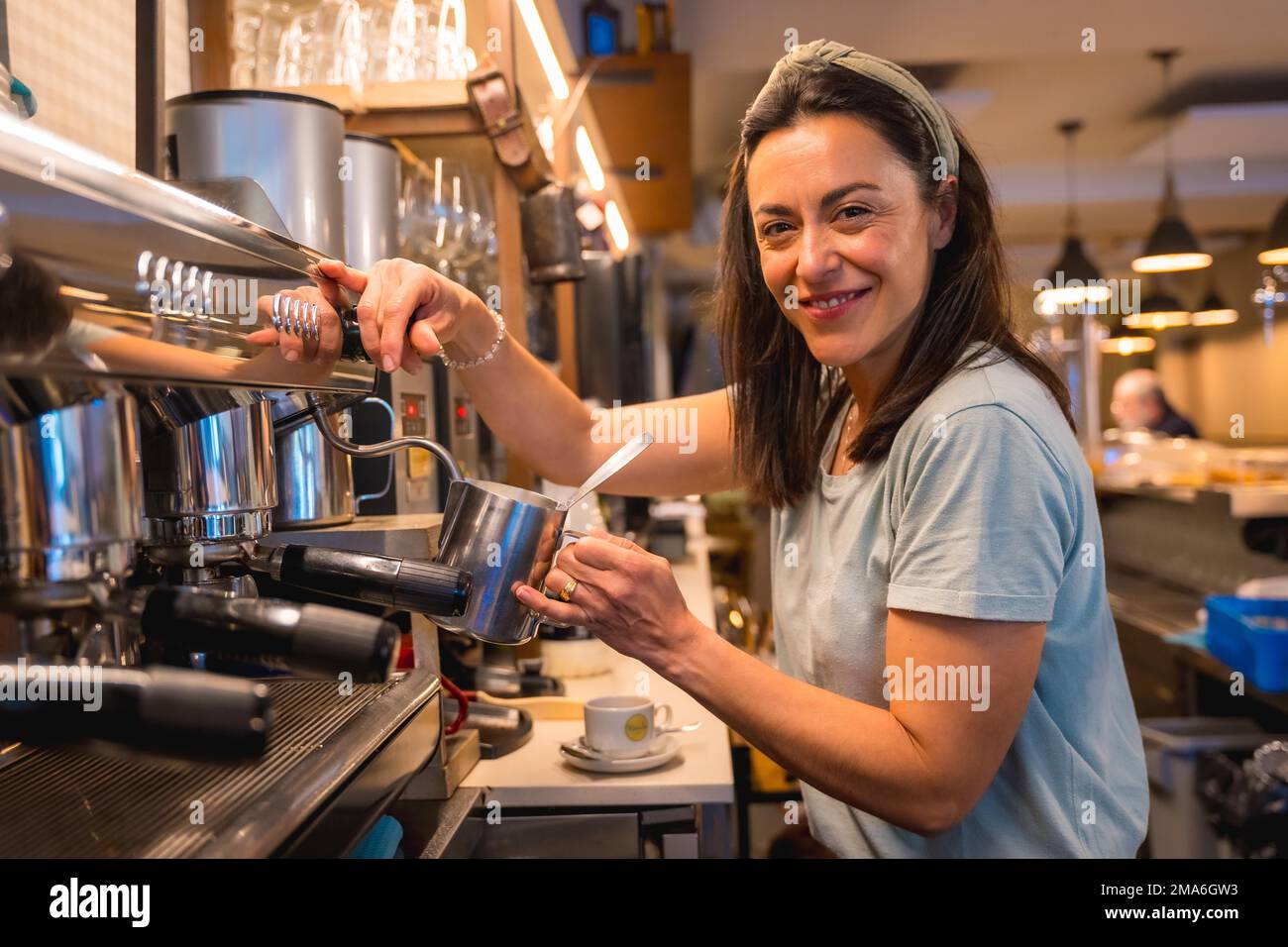 Female cafe owner preparing coffee in a coffee machine, preparing a ...