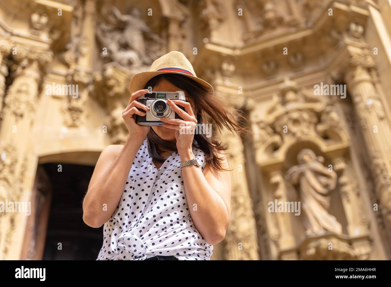 A woman in a hat visiting the city and taking photos with a vintage ...