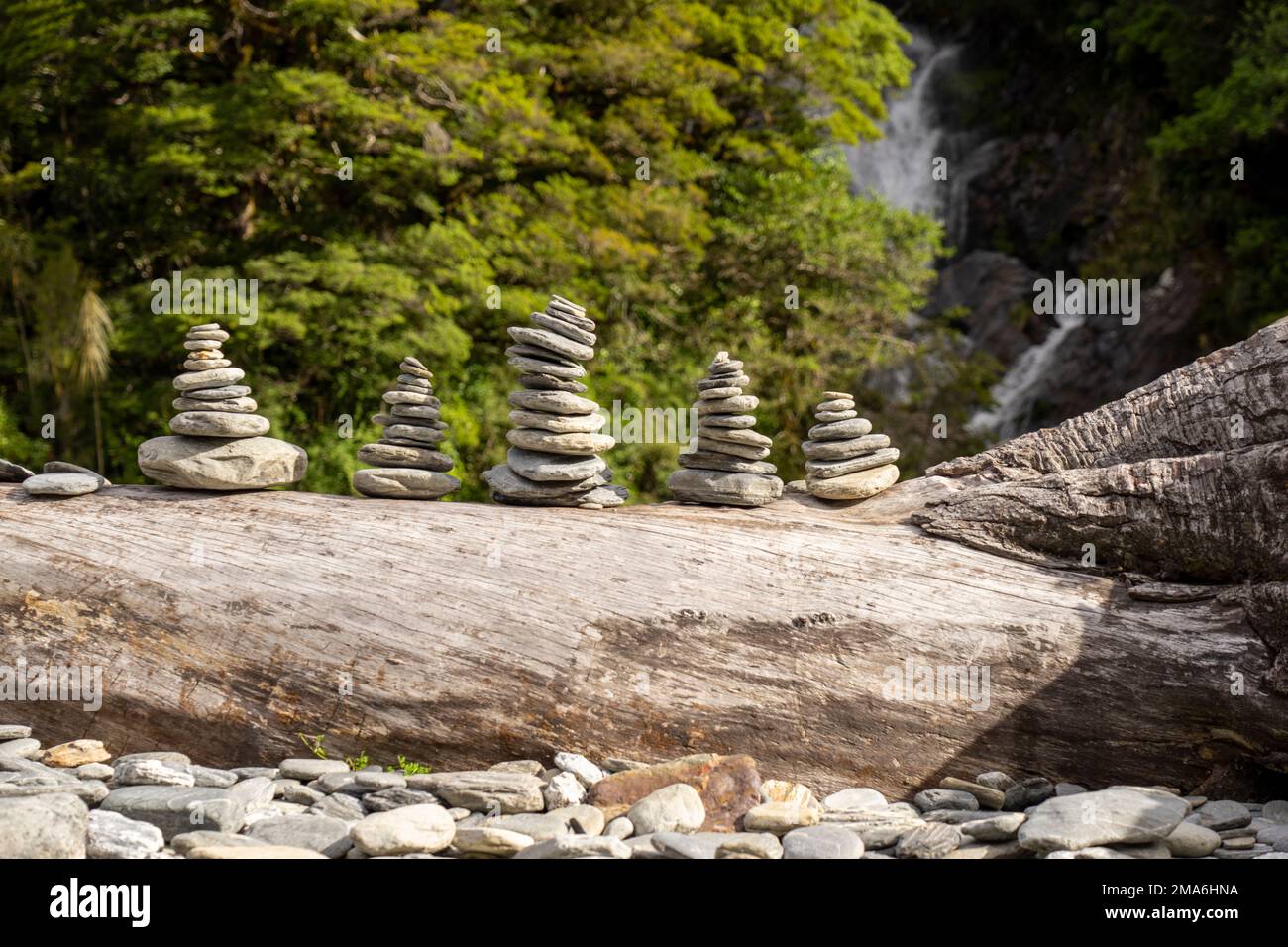 Horizontal shot of many stone pyramids balanced on a old tree trunk on ...