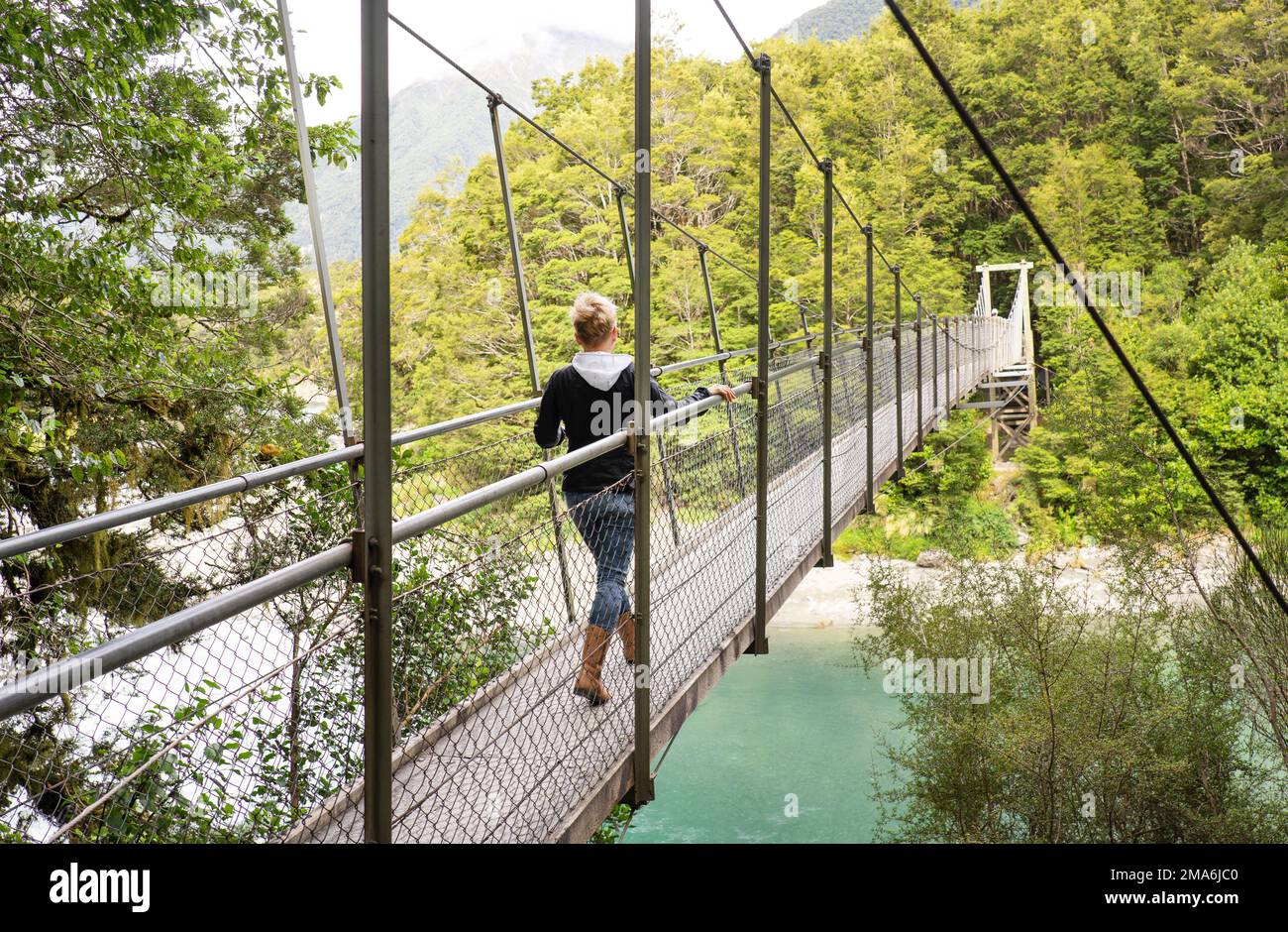 Back view to the white adult Woman crossing Suspension Bridge over the ...