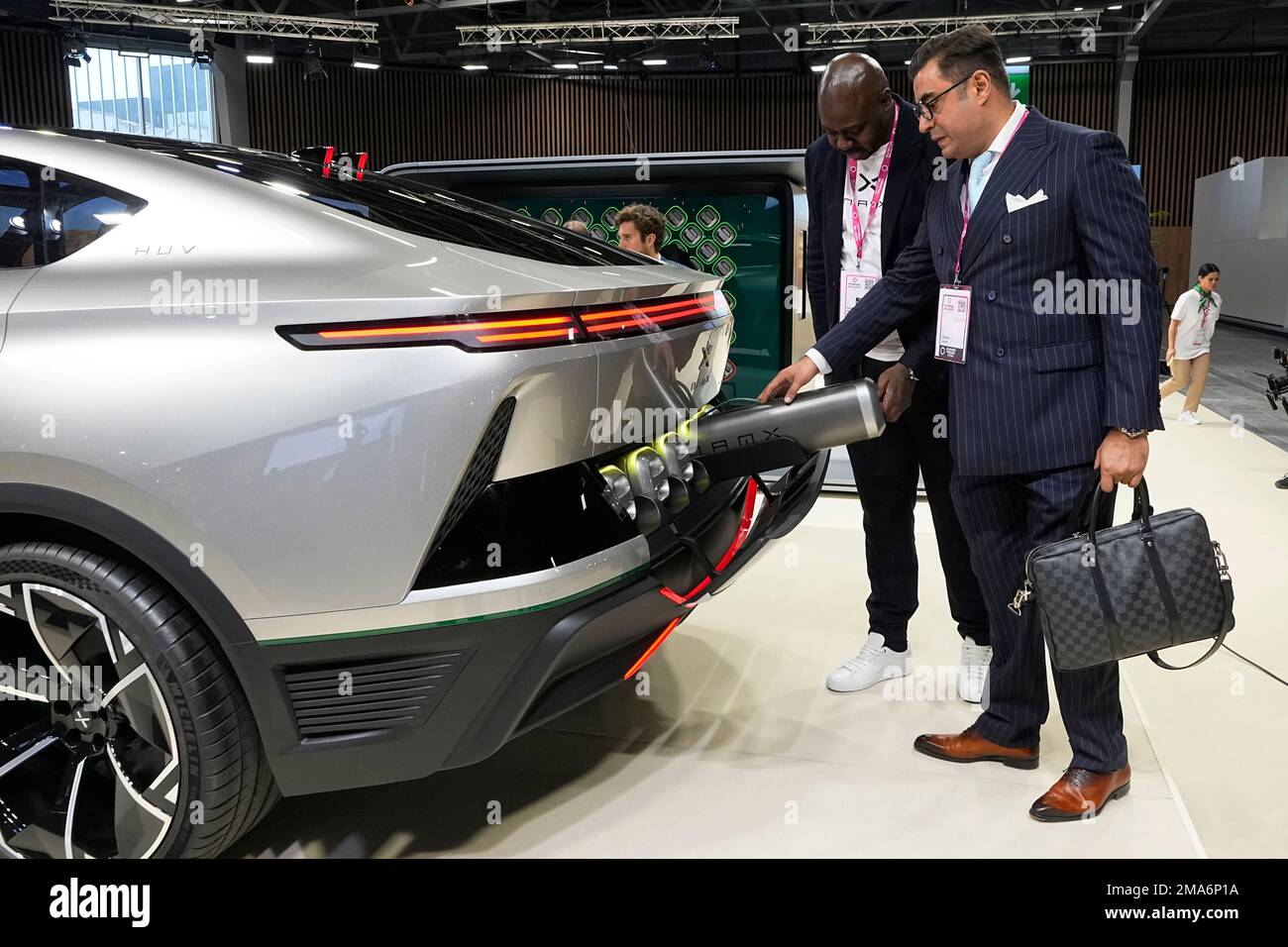 A man shows how to load hydrogen capsules into a NamX SUV car at the ...