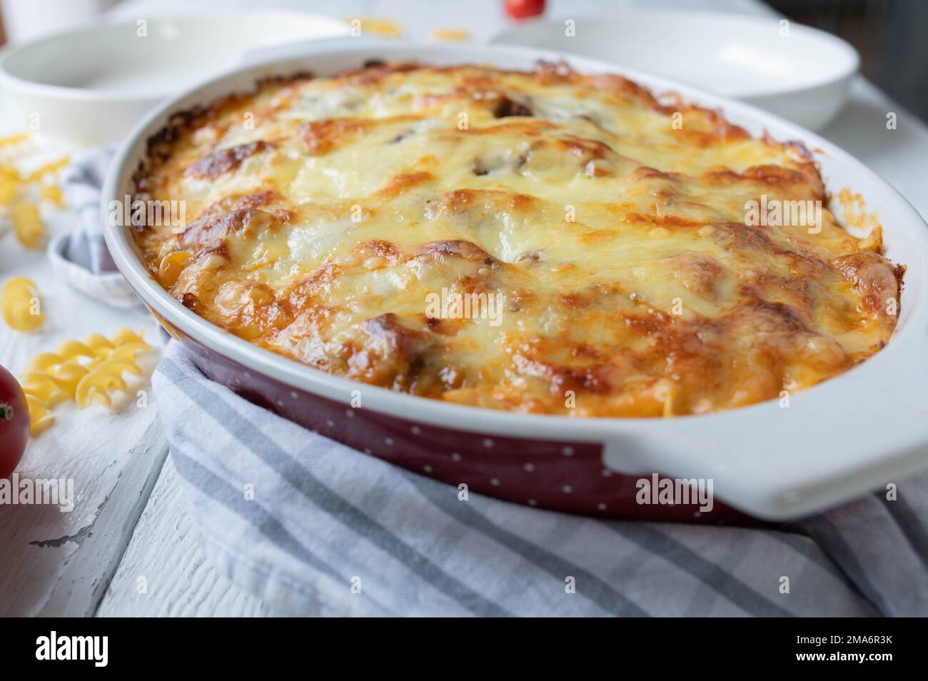 Closed casserole with cheese topping in baking dish on kitchen table ...