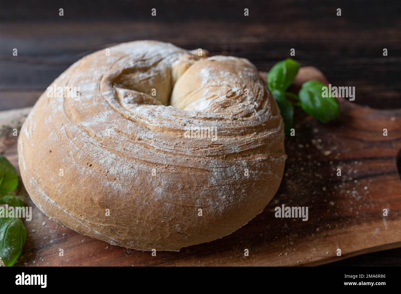 Round loaf of ciabatta bread on dark and rustic background. Closeup and ...