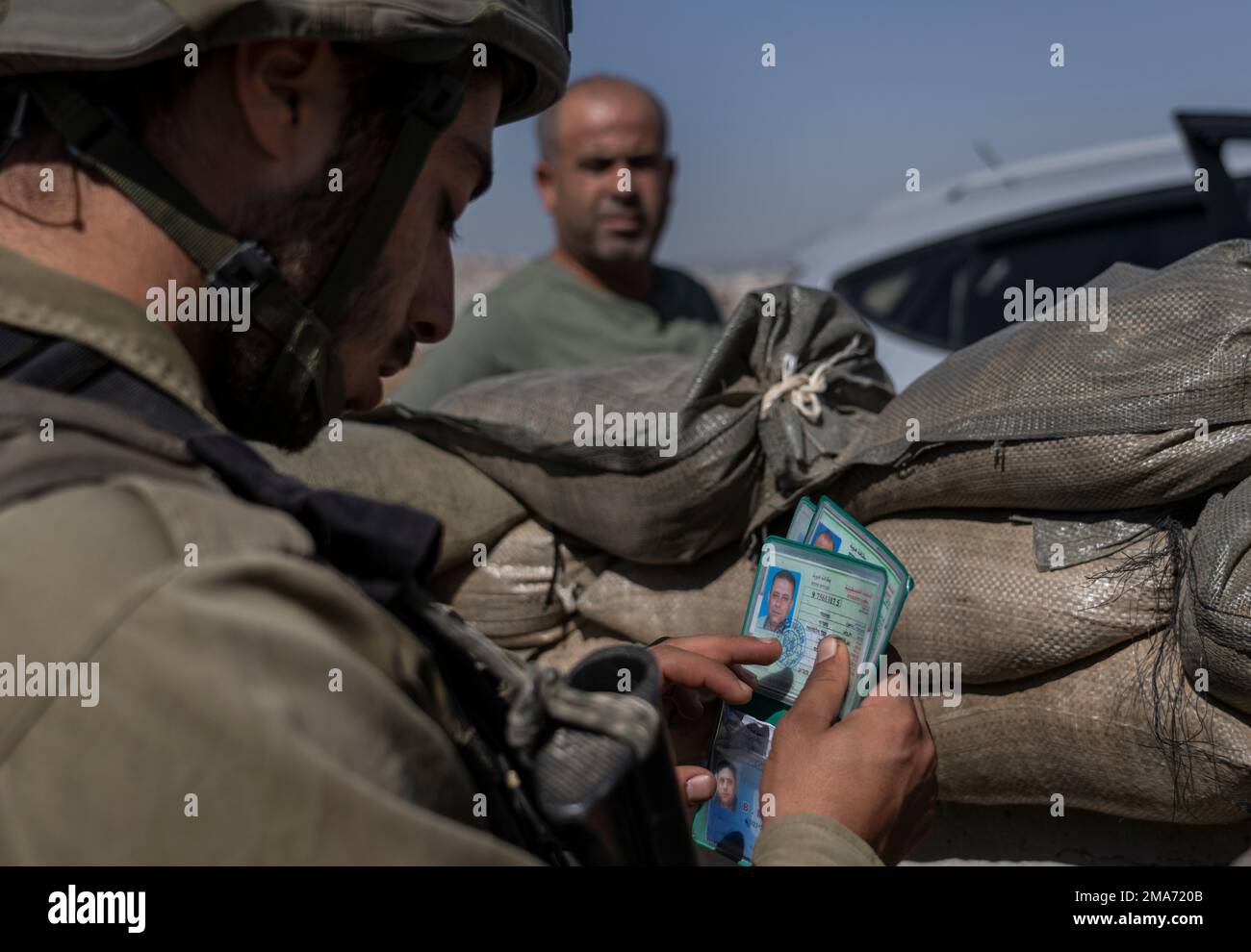 An Israeli Army soldier checks a Palestinian man's identification card ...