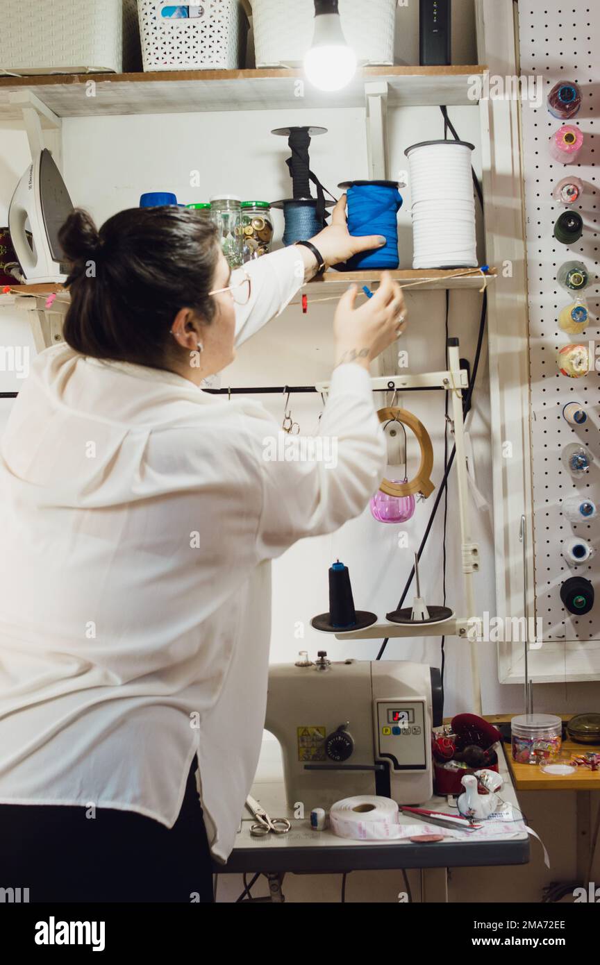rear view of young entrepreneur woman standing working in her homemade ...