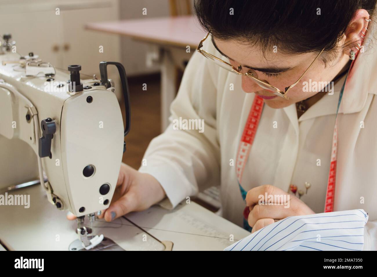 young seamstress woman in her workshop, sitting setting up the sewing ...