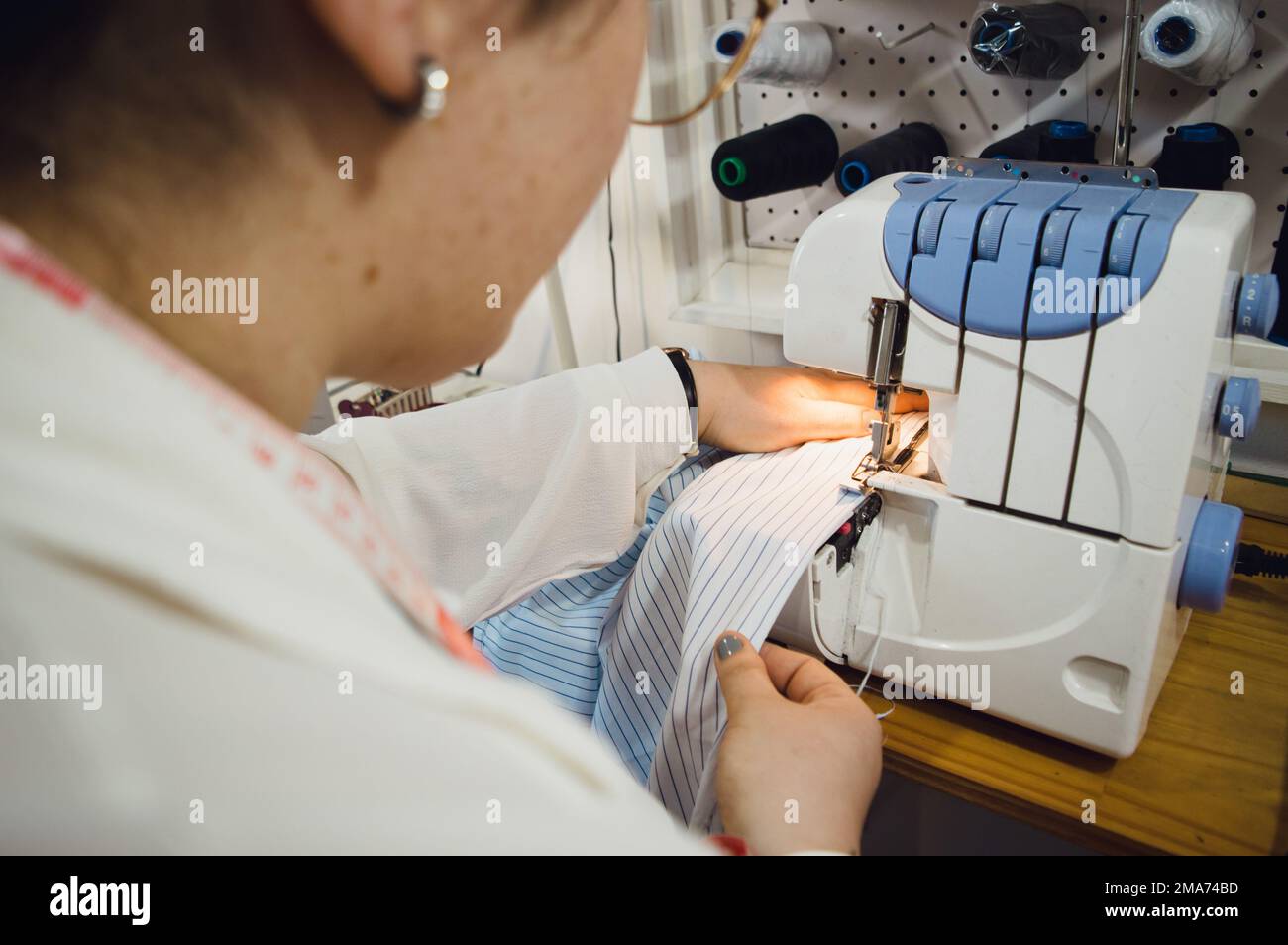 Rear view of a young Argentinian woman who is sewing a cotton fabric ...