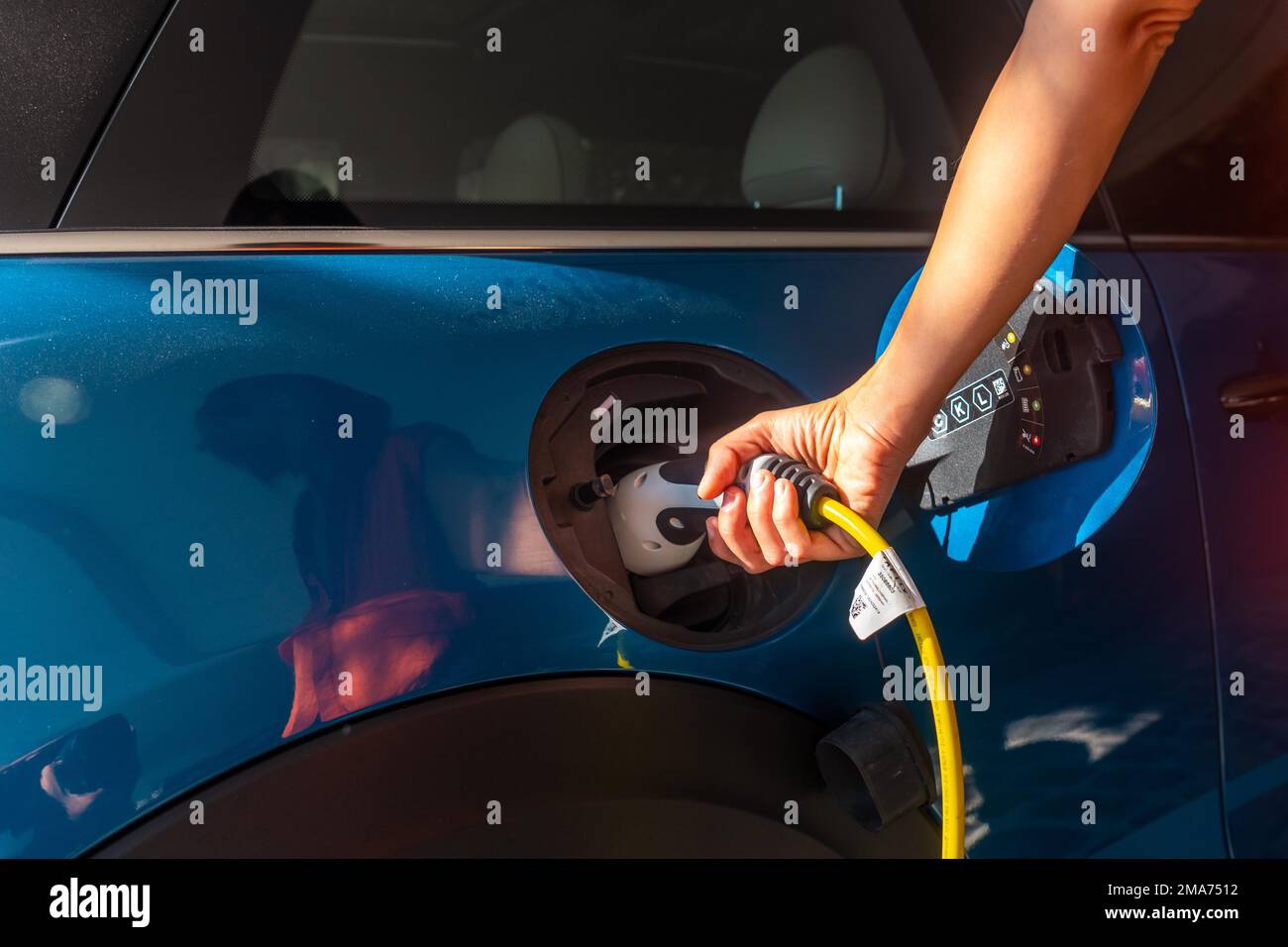 Detail of a hand holding an electric car charging the batteries in the ...