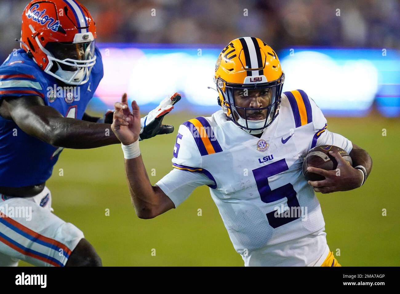 LSU quarterback Jayden Daniels (5) slips by Florida linebacker Brenton ...