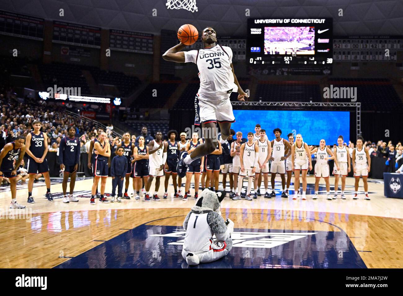 Connecticut's Samson Johnson leaps over the Husky mascot to dunk during ...
