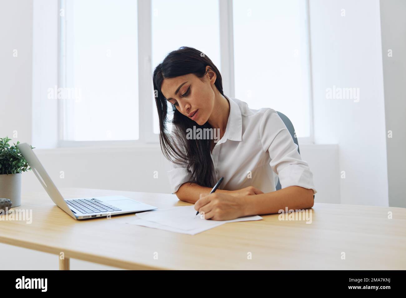 A woman works and learns by writing down text on paper with a pen and ...