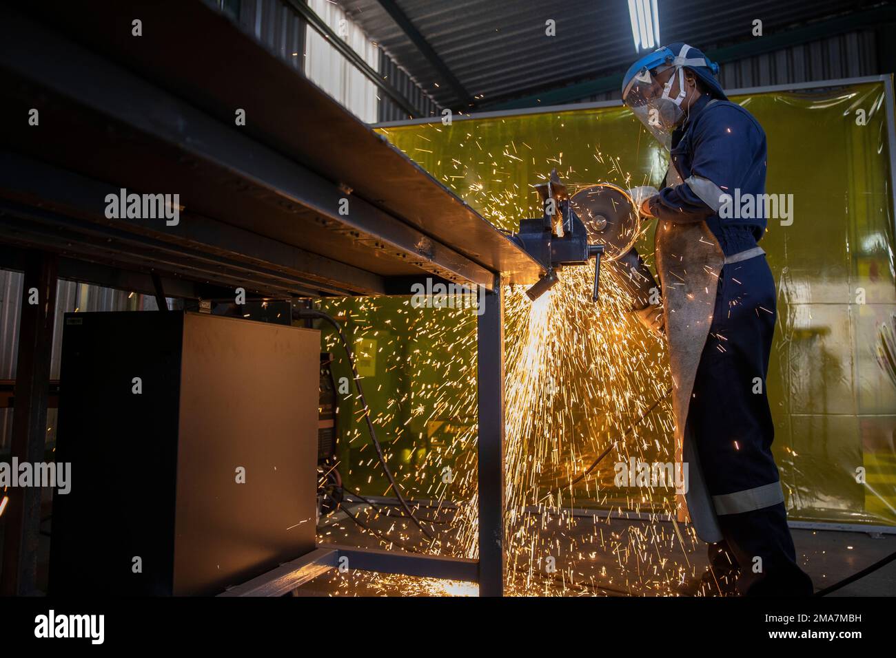 An African man grinding with a cutting machine that leaves golden ...