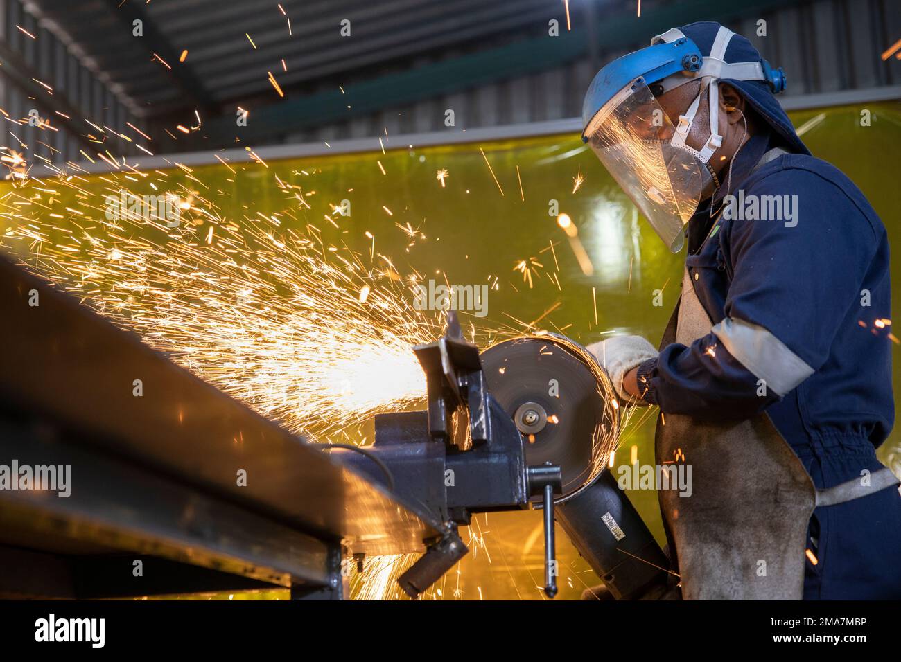 An closeup of an African man grinding with a cutting machine that ...