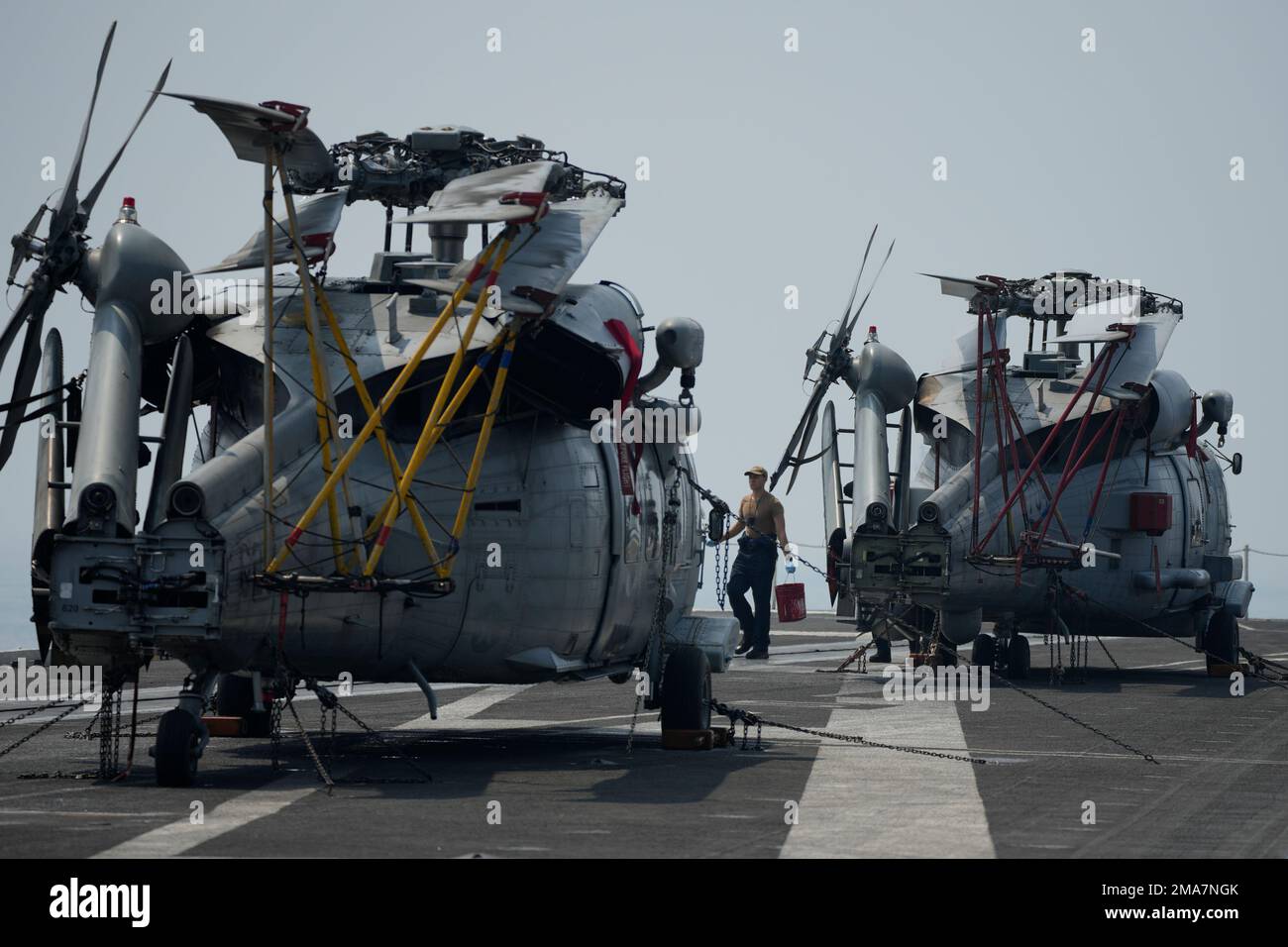 A US Navy sailor walks past MH-60 Sea Hawk helicopters on board the US ...