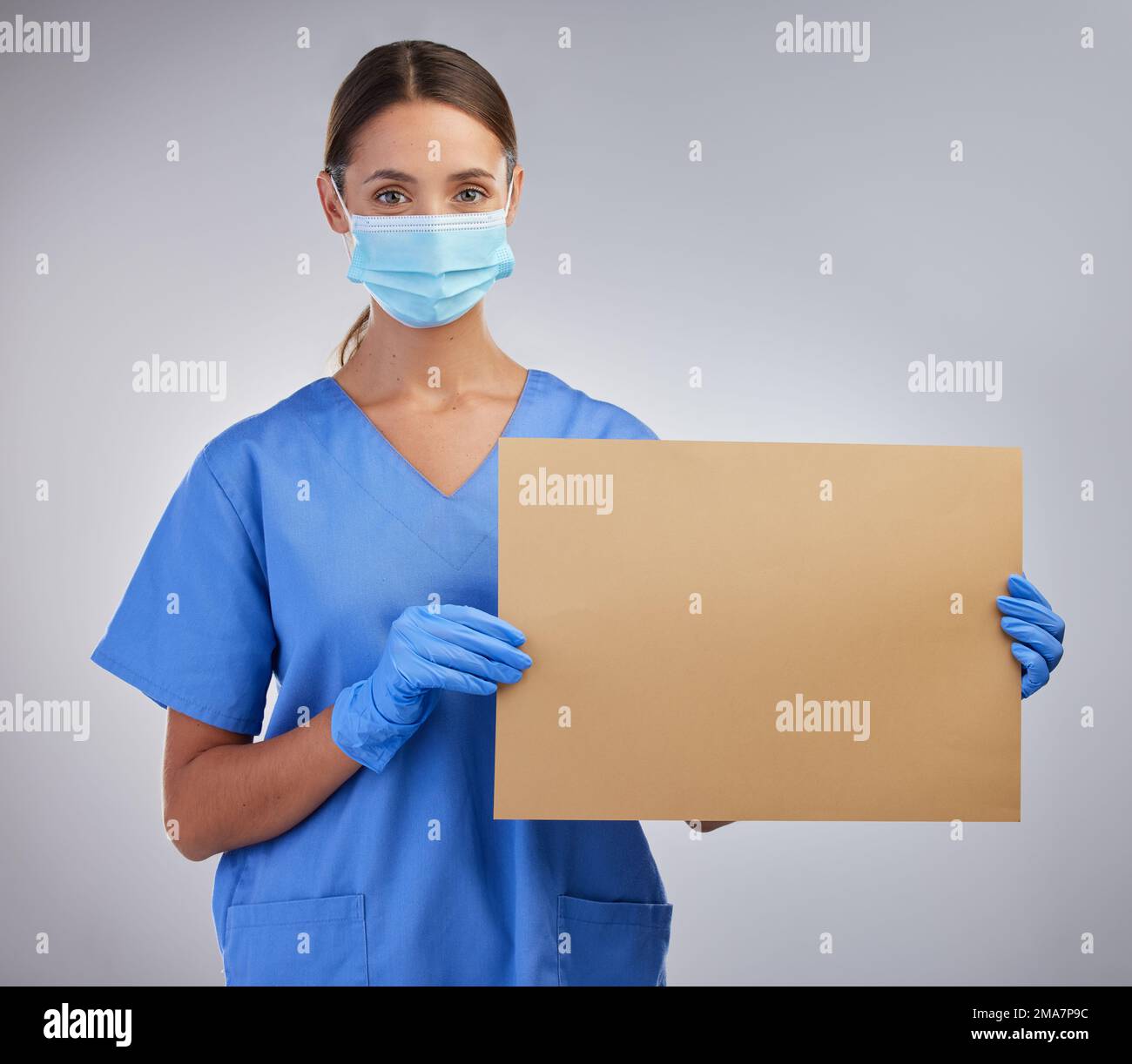 Help us to help you. a female nurse holding a board for signage against ...