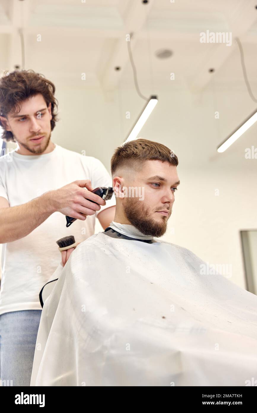 Barber trim hair with clipper on handsome bearded man Stock Photo - Alamy